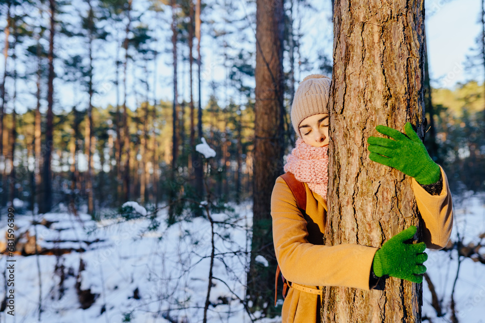 Nature lover hugging trunk tree with green mittens in winter woods ...