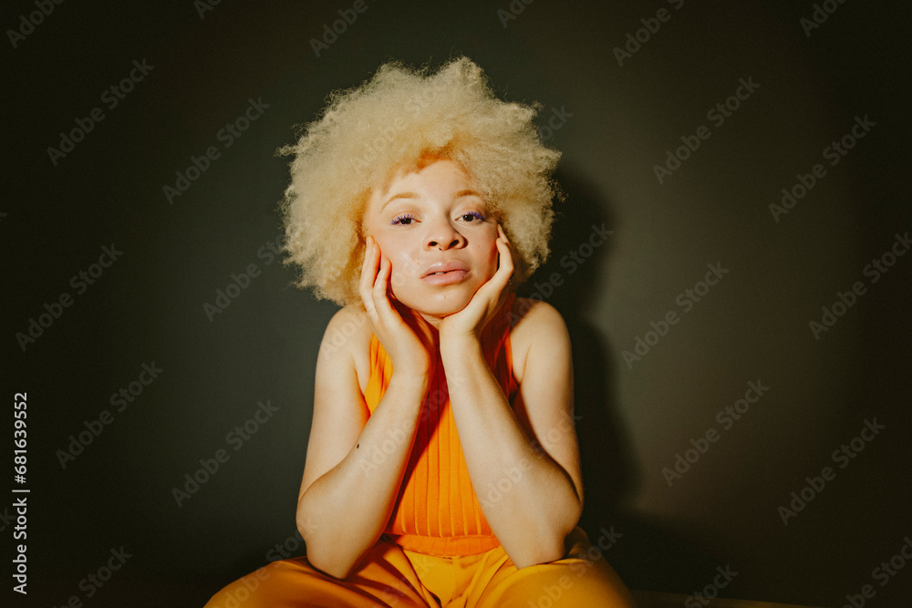 Confident young woman with albinism in yellow outfit in living room ...