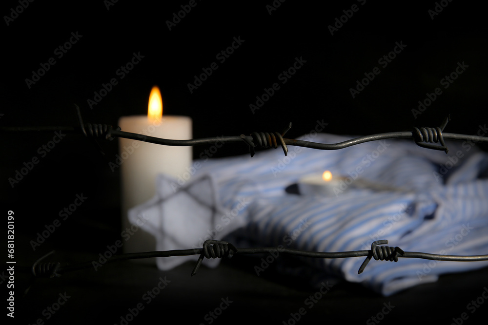 Barbed wire with burning candles and prisoner uniform on dark ...
