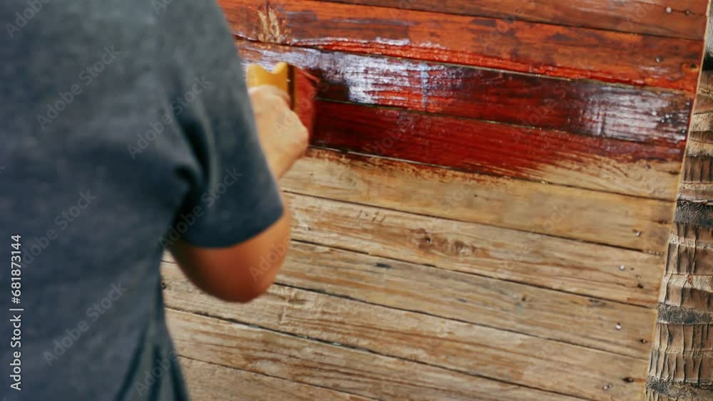 Hand of woman applying wood protection oil on boards with paint brush ...