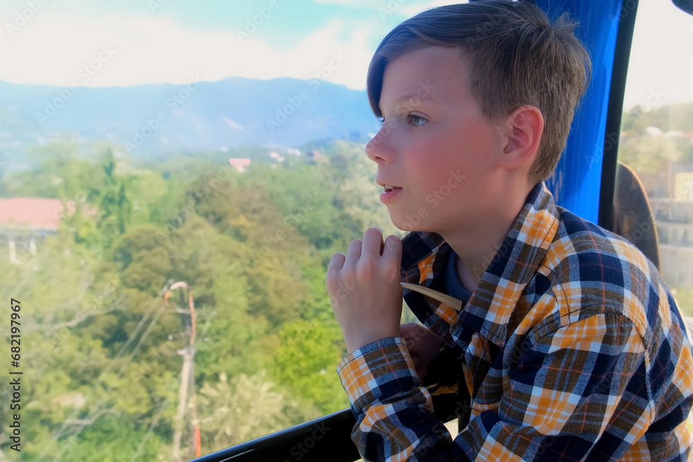 Interested teen boy tourist sitting in funicular cabin of cable car in ...