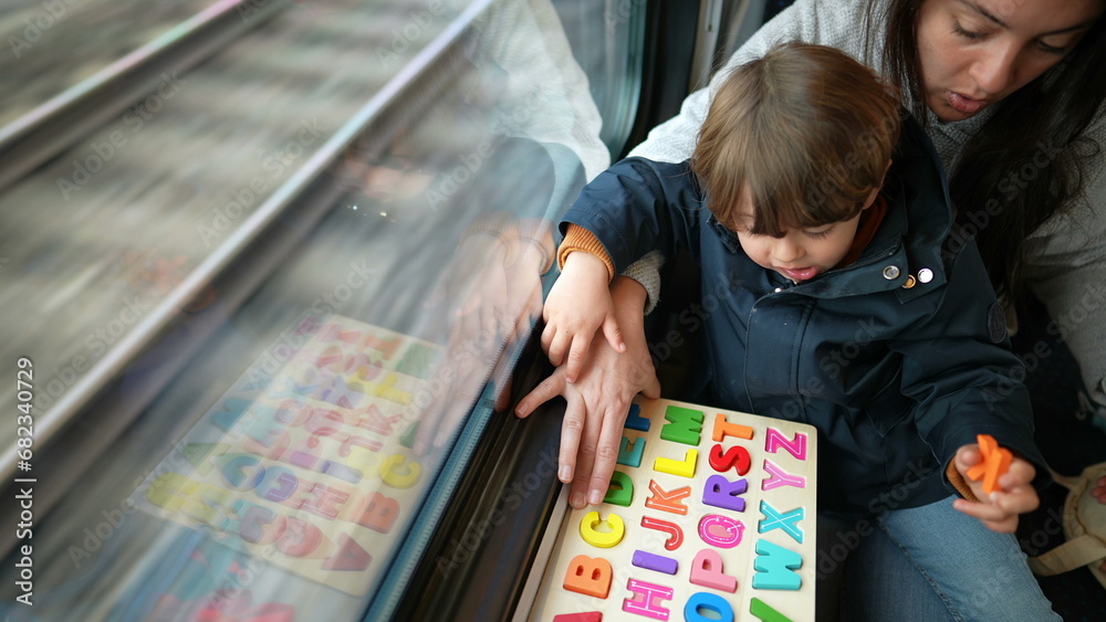 Little one perched on mom's lap in train, diligently working on school ...