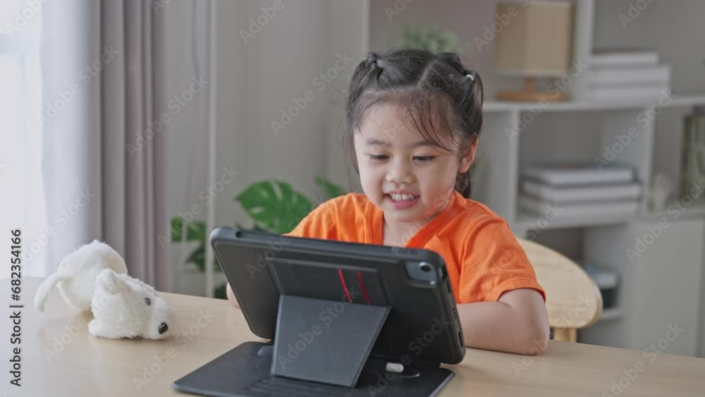 Asian child girl looking using and touch tablet display screen. Baby ...
