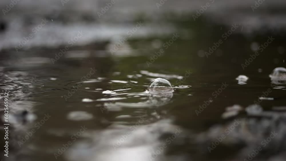 Autumn rain scene: Droplets fall slowly into a puddle, bubbles emerge ...