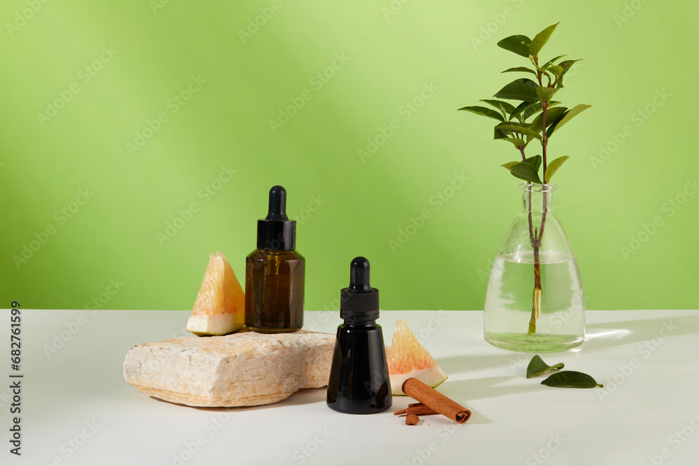 Serum bottle is placed on the table with pomelo, stone podium and ...