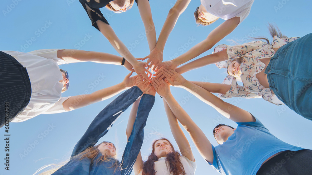 Friends putting their hands together in a sign of unity and teamwork ...