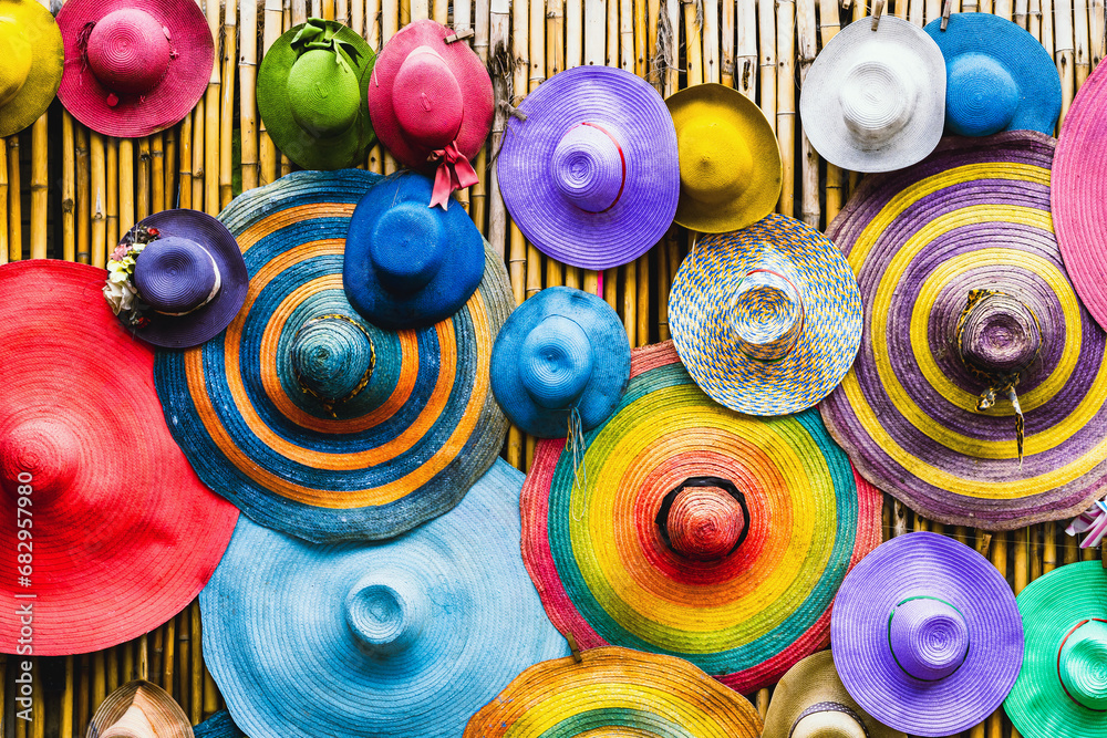 Variety of fashionable and colorful hats hanging on bamboo backdrop of ...