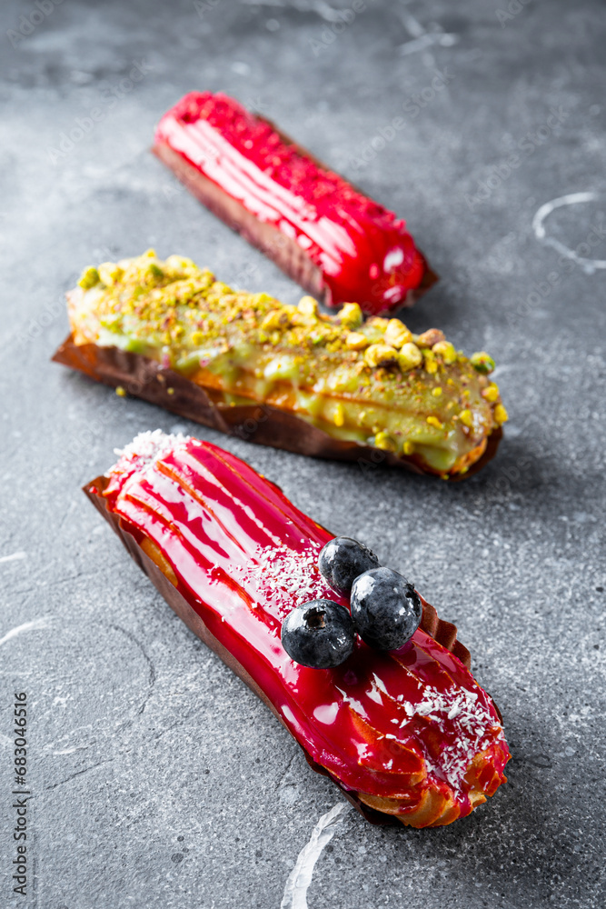Three eclairs with different fillings - berry and pistachio on a ...