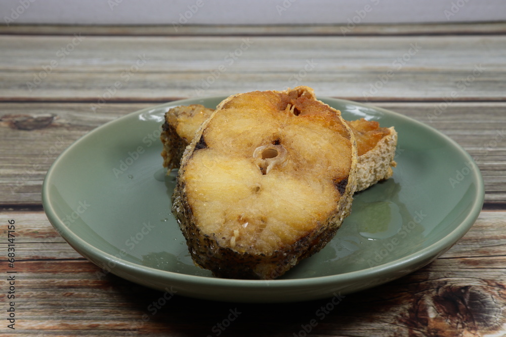 Pile of deep fried barracuda fish fillet serving on the plate. Famous ...
