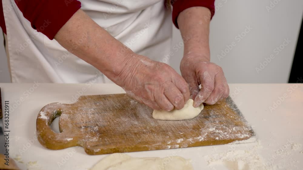 Close up view wrinkled hands elderly woman sticking dough after putting ...