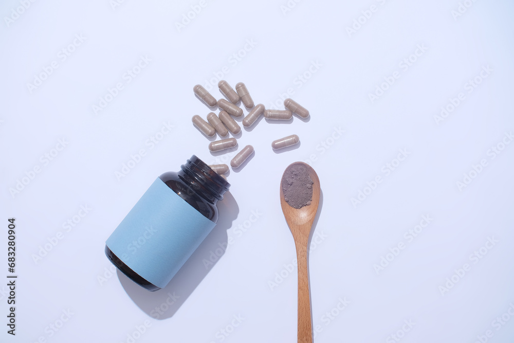 Silver hard capsules are poured onto the table from an unbranded pill ...