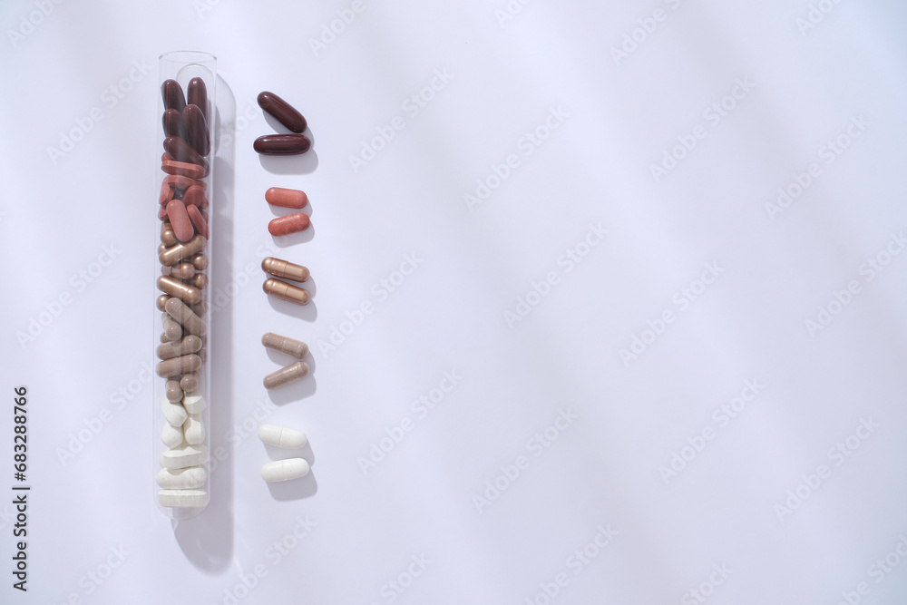 Different types of capsules arranged in a test tube on background ...