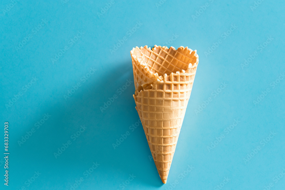 The image shows a single ice cream cone placed on a blue background ...