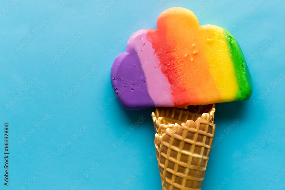 The image depicts a colorful ice cream cone with rainbow-colored scoops ...