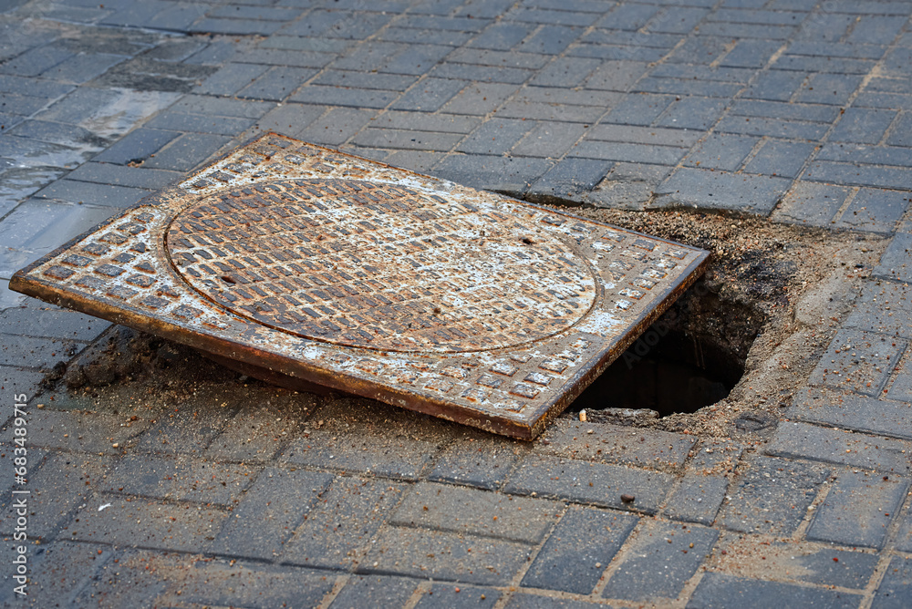 Broken manhole, pothole in paving slabs, damaged sidewalk, shifted and ...