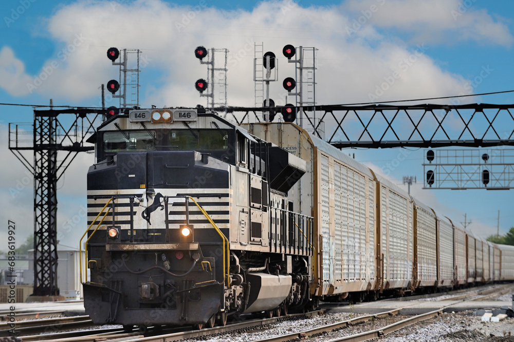 A Norfolk Southern Railway locomotive leads an auto rack train under a ...
