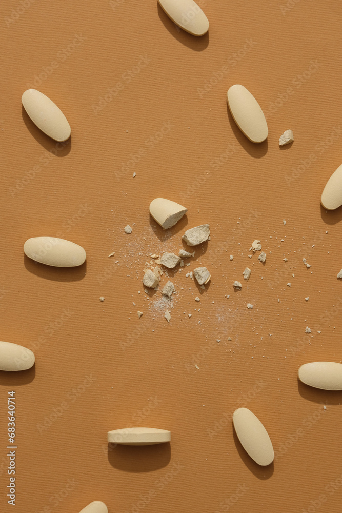 A crushed tablet and the other tablets are displayed on a brown ...