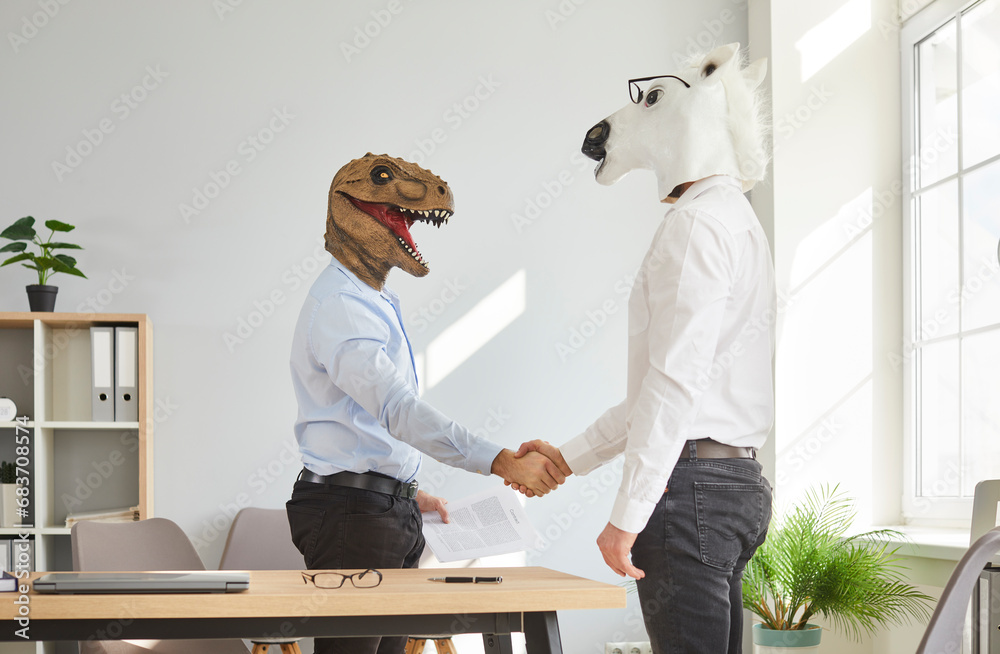 Two colleagues in animal head masks handshaking after meeting ...