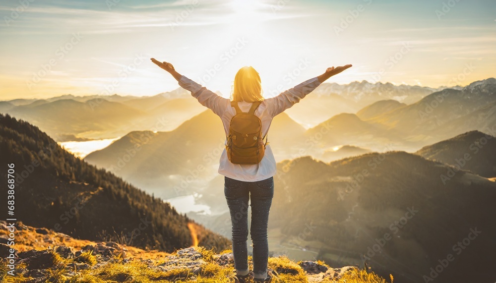 Success story: A woman on top of the mountain with arms open to a ...