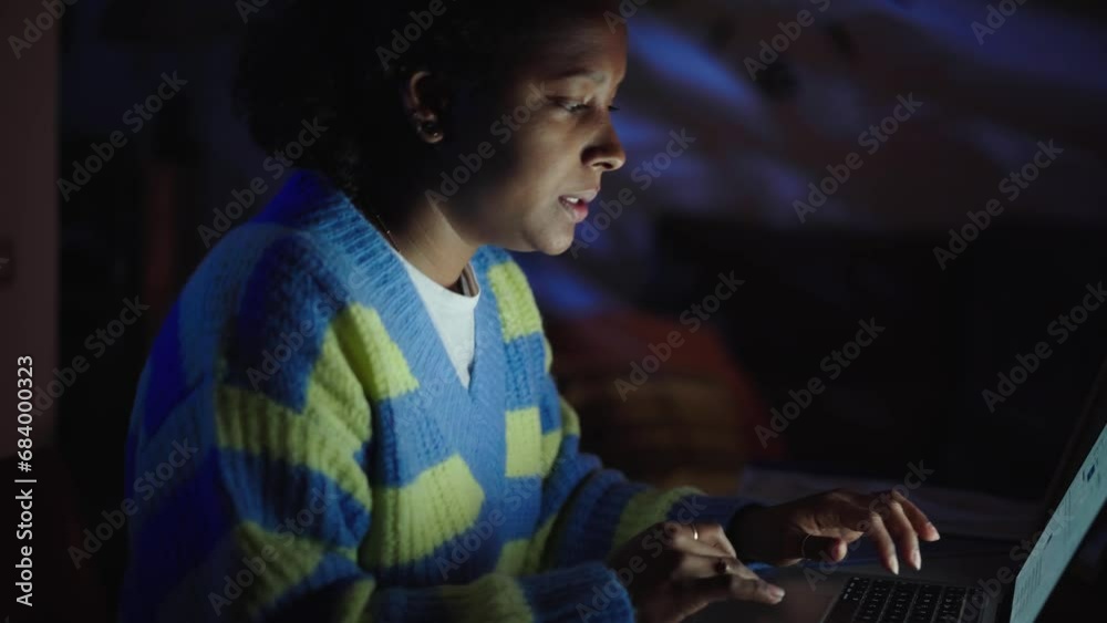 Side view concentrated young Latin girl using laptop at home night ...