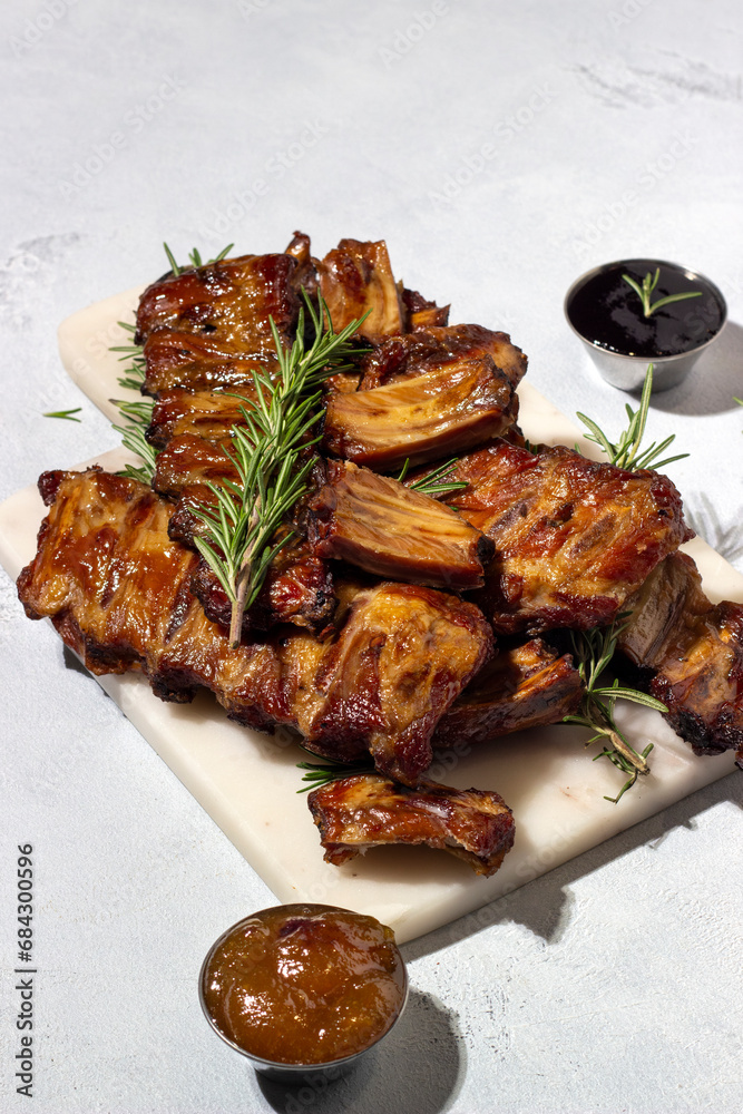 Smoked pork ribs with rosemary on a marble cutting board. light ...