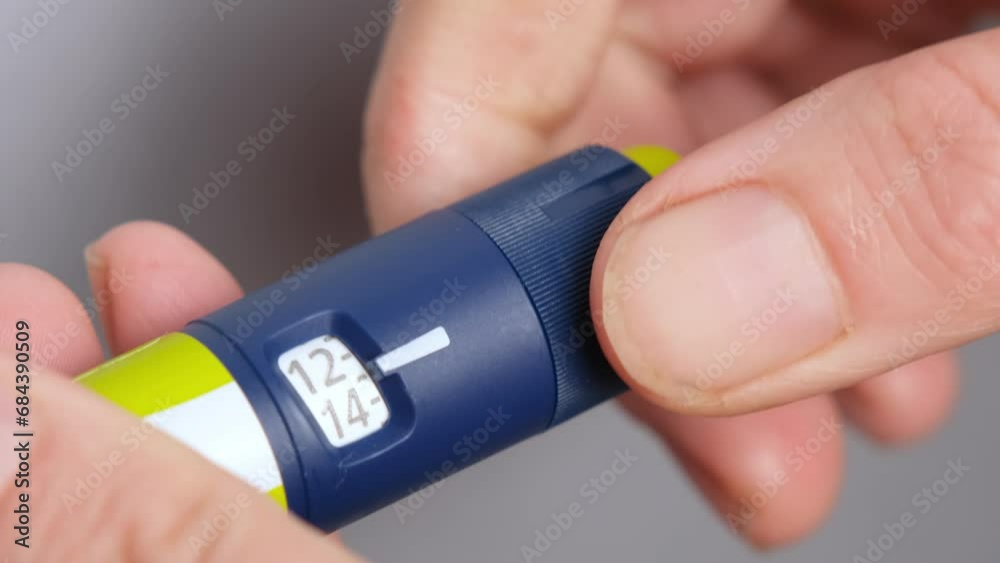 Close up on hands turn knob on insulin pen and dial up insulin dose for ...