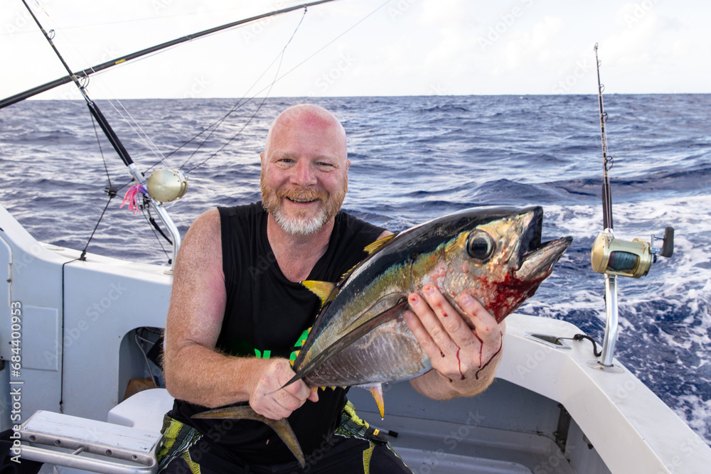 Happy man holding a fresh caught bigeye tuna fish on a fishing boat in ...