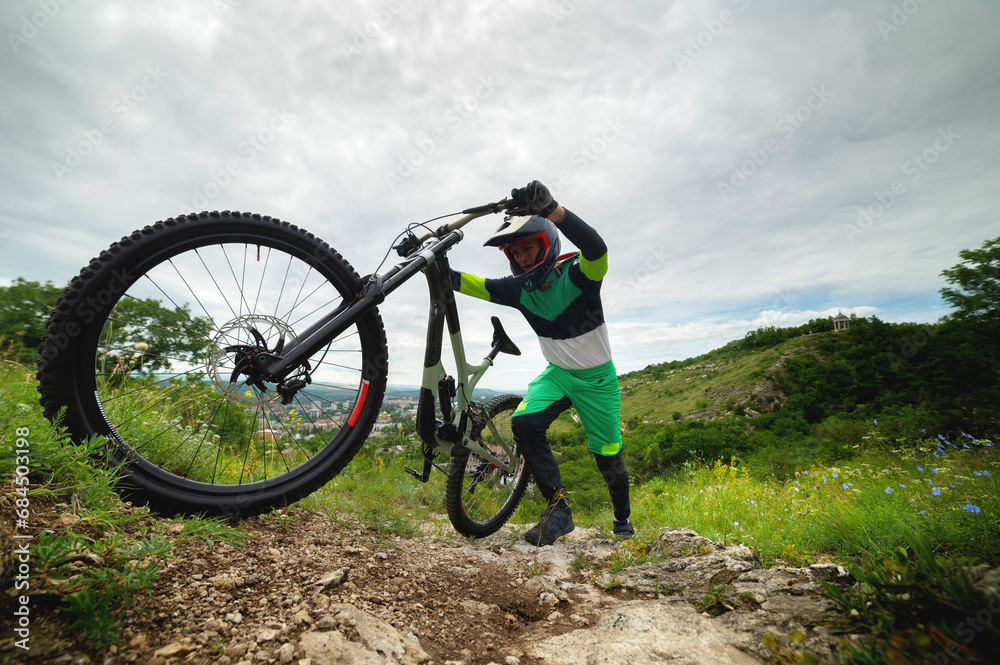 A man pushes a mountain bike up a hill. Adventure travel by bike. Guy ...