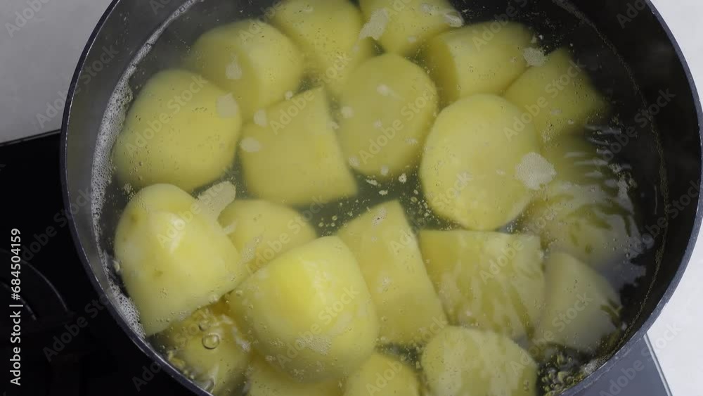 Boiling pot with peeled potatoes on a gas stove, simmering in hot water ...