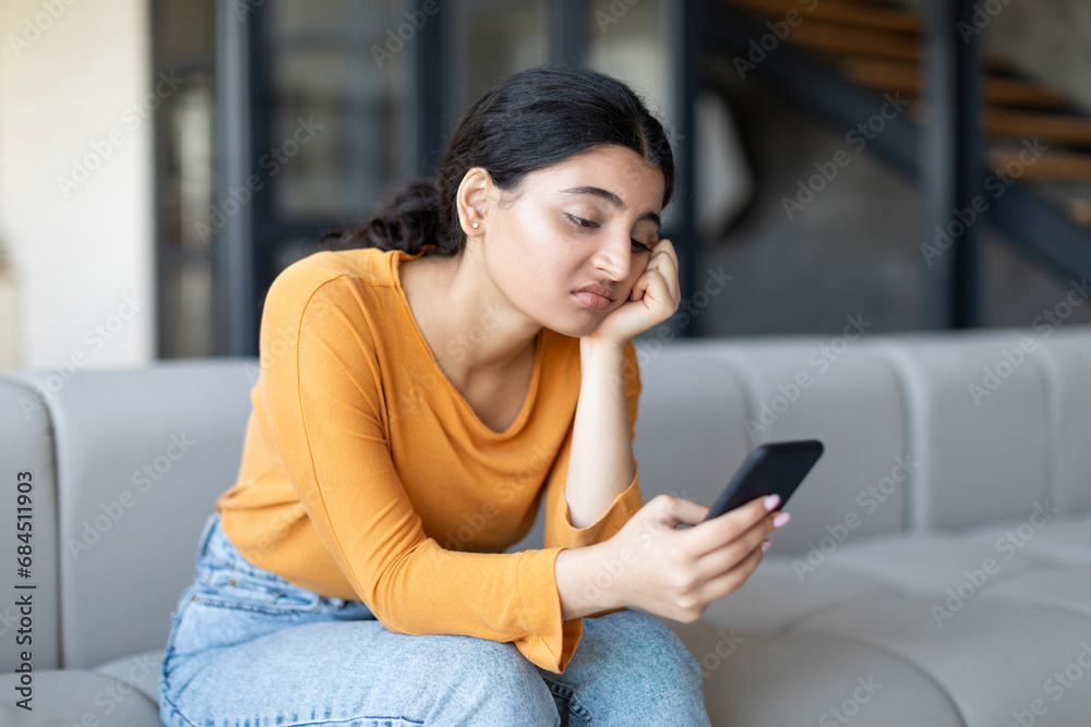 Boring Content. Portrait of bored young indian woman using smartphone ...
