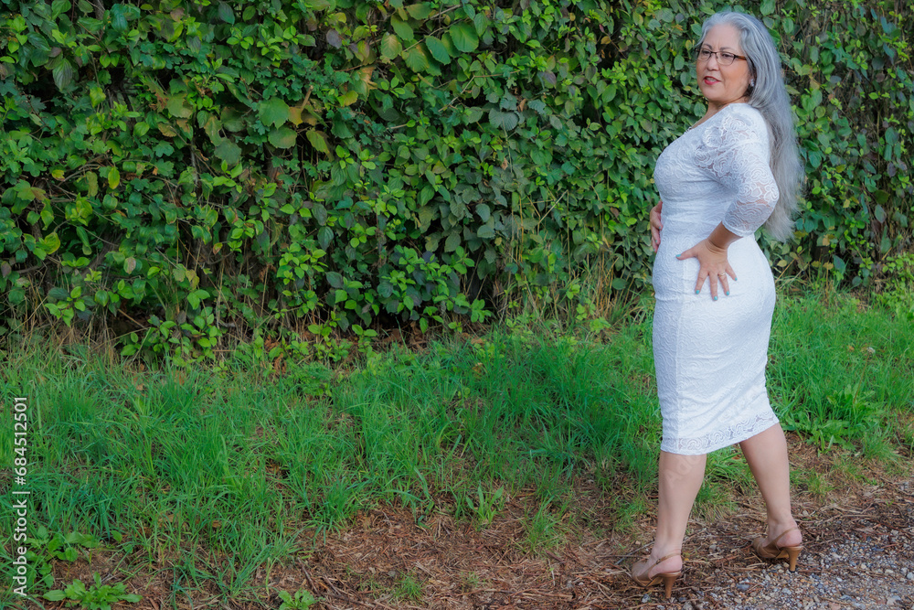 Full body mature woman in elegant white dress standing with torso ...