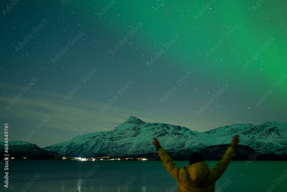 Person reaching up to green Northern Lights Dancing in Arctic skies ...
