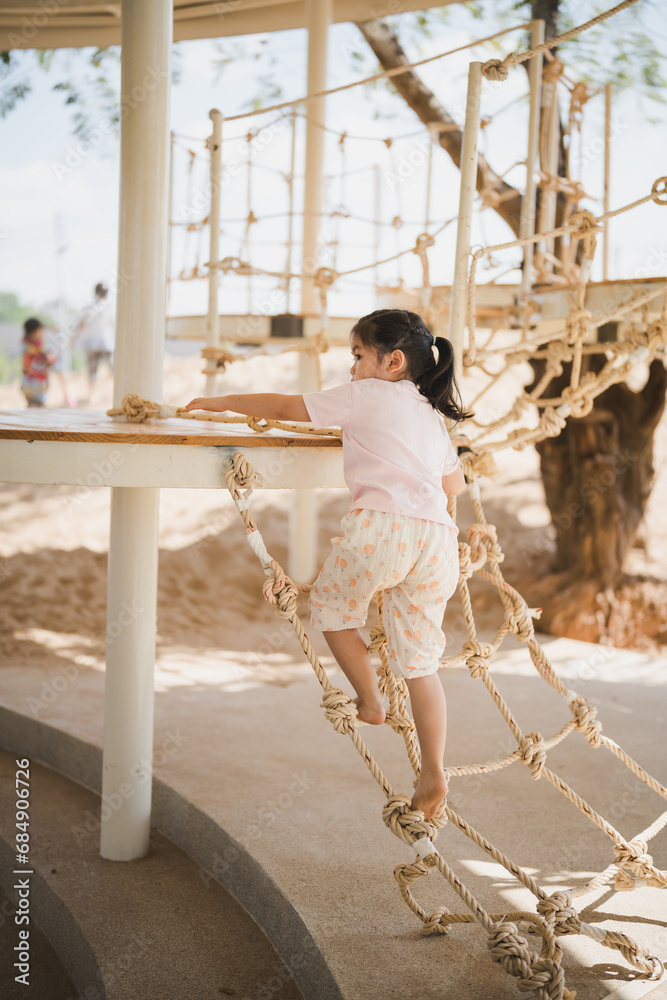 Asian girl children climbing rope net at the playground in the cafe for ...