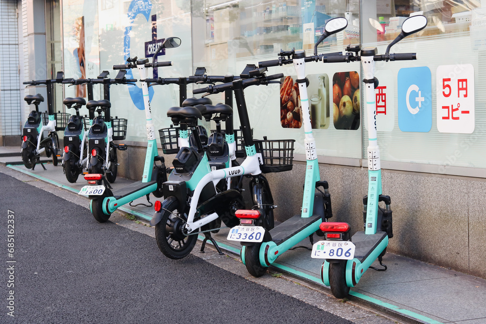 TOKYO, JAPAN - November 12, 2022: A row of Luup rental e-scooters and e ...