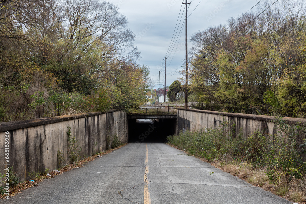 Decrepit road going under a railroad overpass in the deep rural south ...