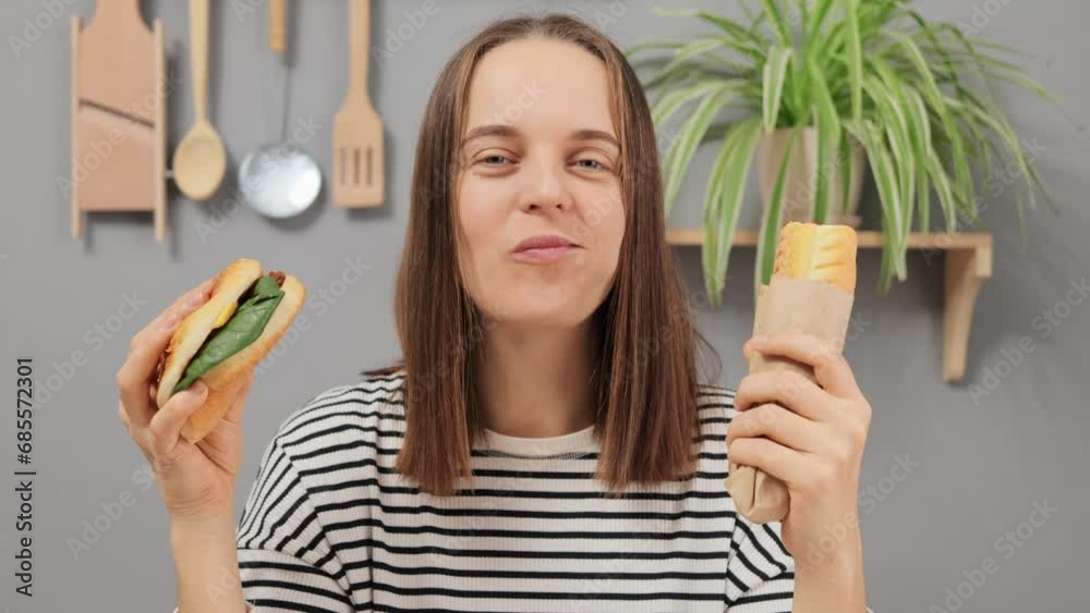 Extremely hungry woman in striped shirt breaking diet biting hot dog ...