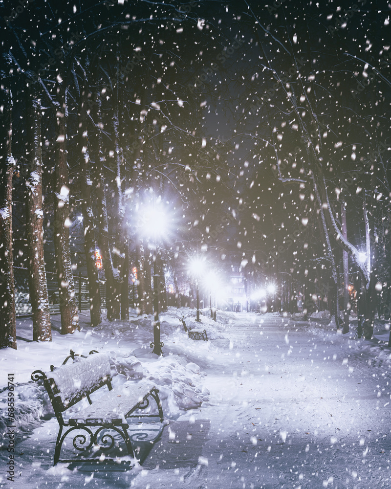 Foto de Snowfall in a winter park at night with glowing lanterns ...