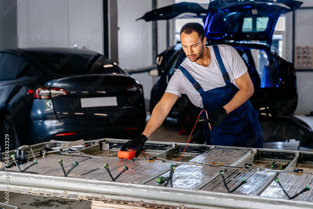 Arabian male technician engages with an EV Car Battery Cell Module ...