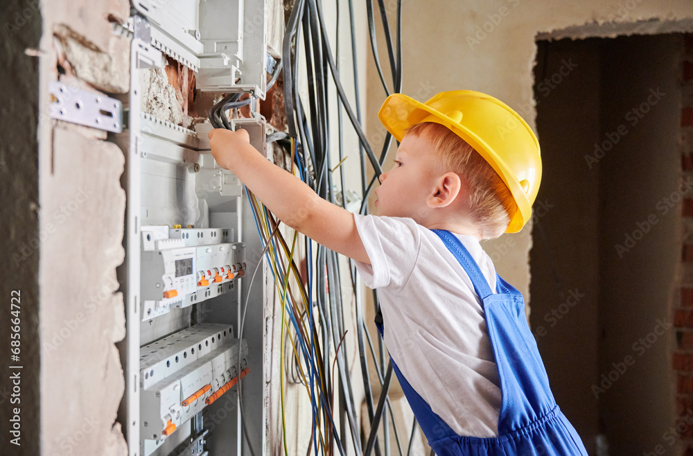 Little boy electrician holding electrical wires while fixing electric ...