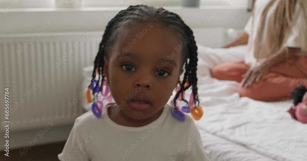 cute small serious African kid girl looking at camera at home recording ...