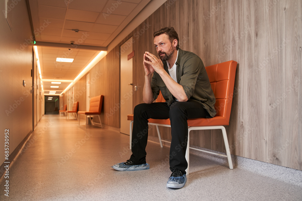 Sad man patient nervously impatiently waiting in the hospital lobby ...