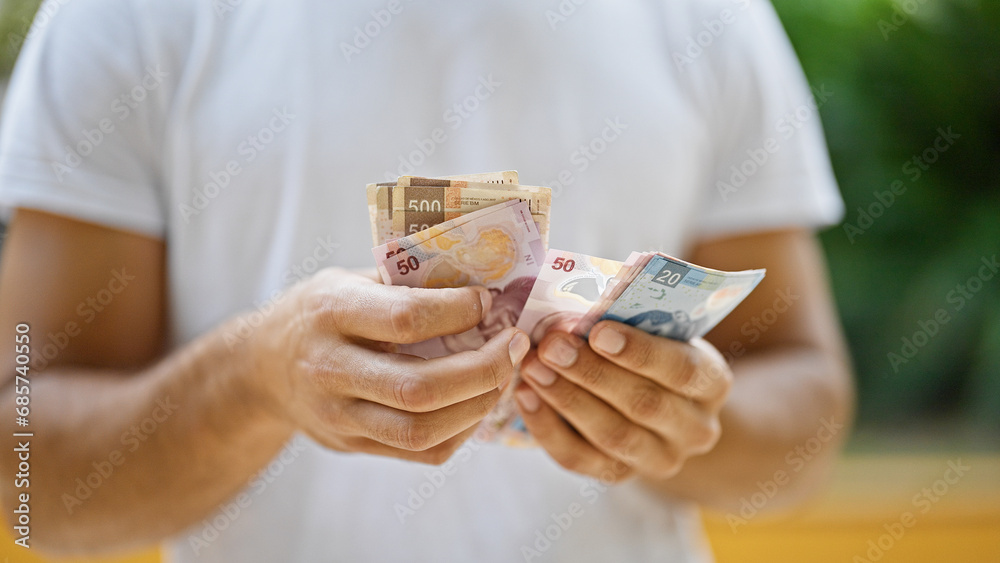 Young hispanic man counting mexican pesos at park 素材庫相片 | Adobe Stock