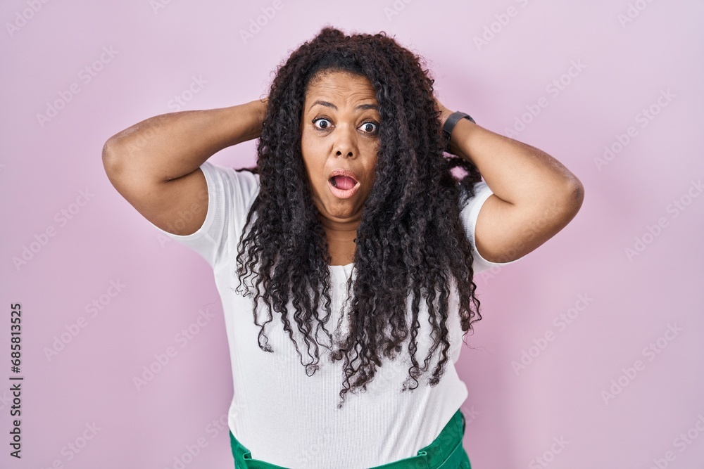 Plus size hispanic woman standing over pink background crazy and scared ...