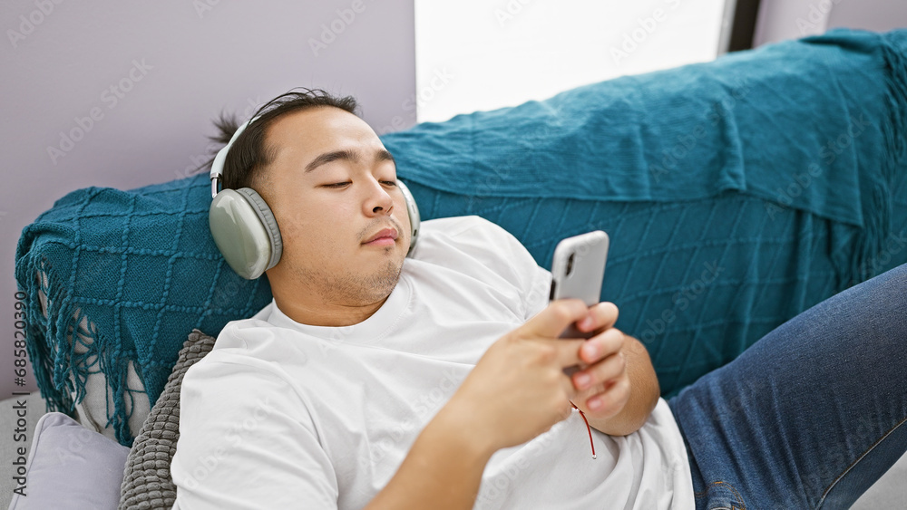 Handsome young chinese man relaxed at home, engrossed in watching a ...