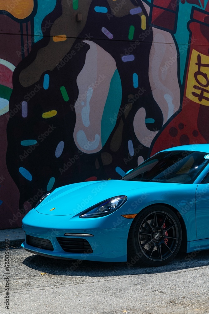 From old to new, Porsche sports cars parked near an art mural in a ...