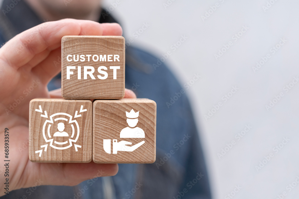 Man holding wooden blocks with icon sees inscription: CUSTOMER FIRST ...
