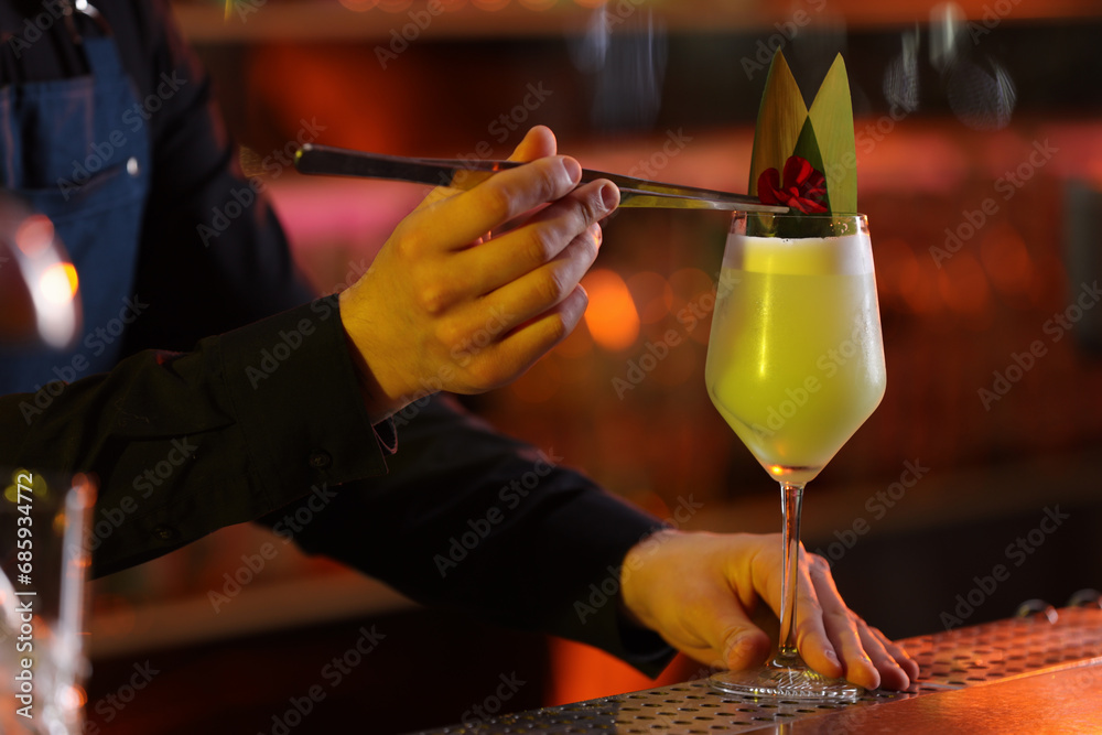 Bartender decorating fresh alcoholic cocktail with flower at bar ...