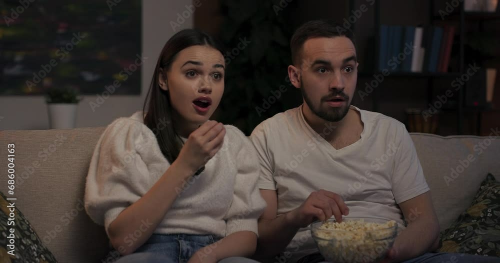 Beautiful couple watching horror movie filled with jump scares tenses ...