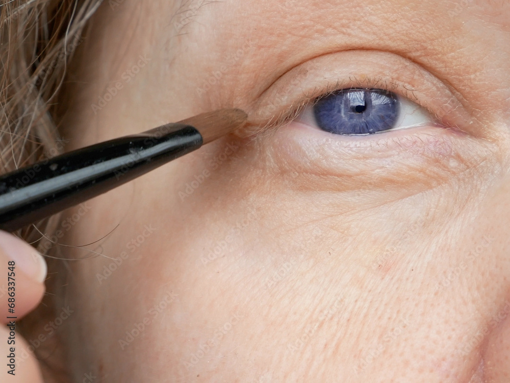 middle aged female's eye with drooping eyelid making eyebrow makeup ...