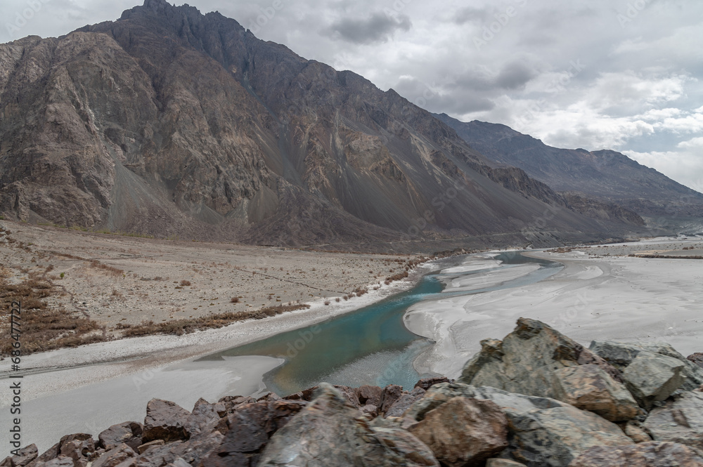 Valley between mountains on a cloudy day. A Dried river trains of Shyok ...